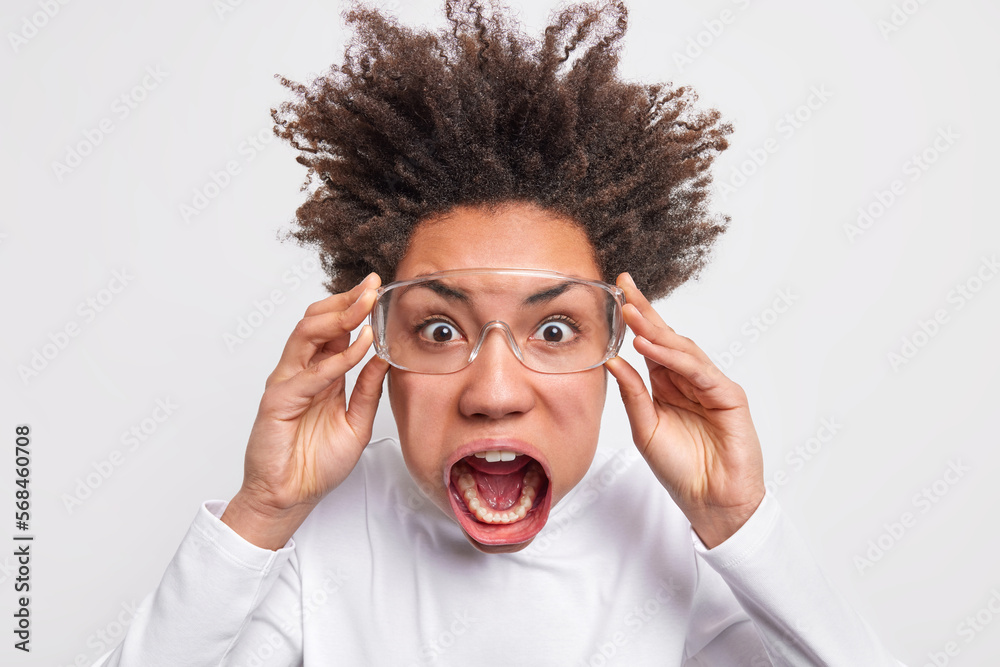 Shocked terrified young woman stares through transparent eyeglasses has ...