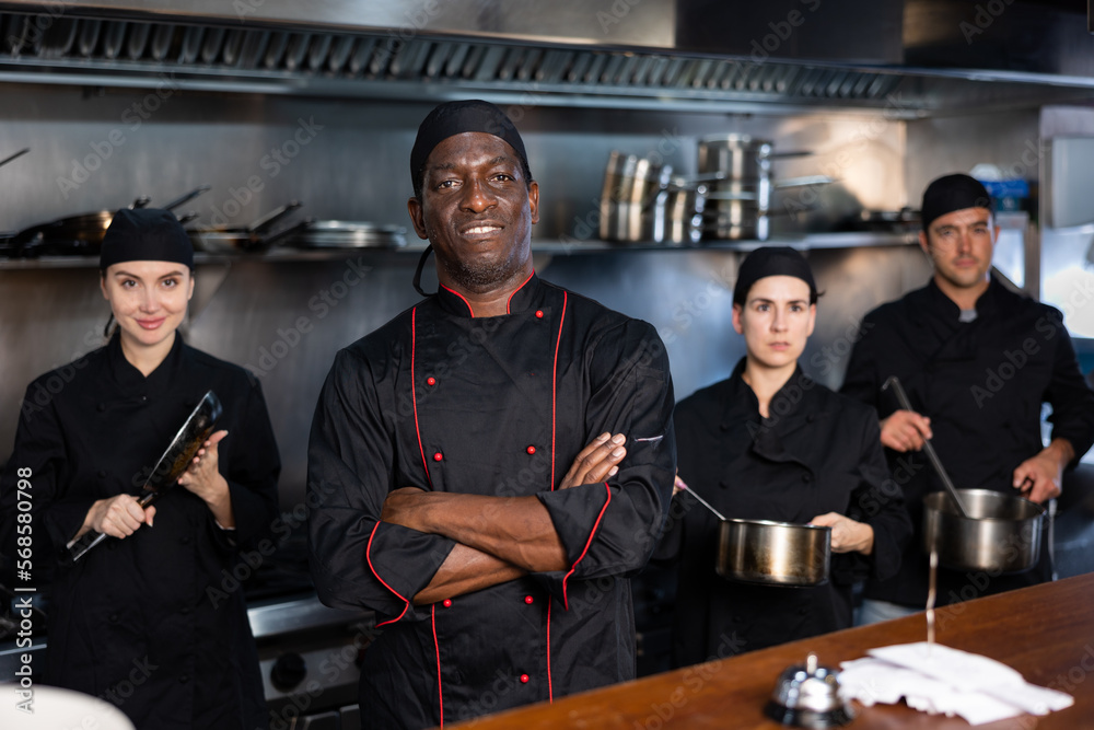 Foto de Team of focused chefs with African man head chef posing ...