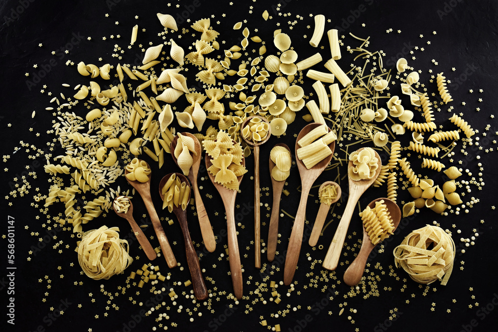 Mix of pasta shapes varieties on dark background: penne and fusilli ...