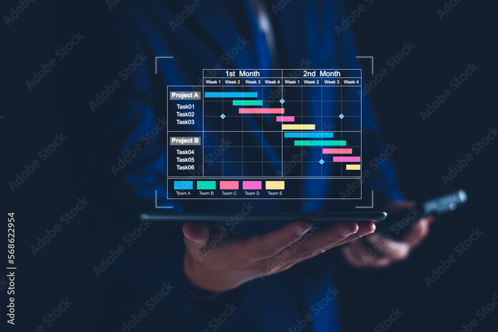 Project manager working on tablet and updating tasks and milestones ...