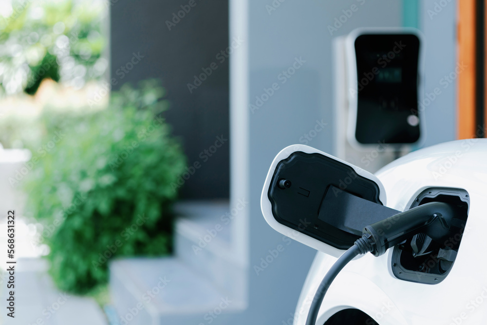 Closeup electric vehicle plugged-in with cable from charging point ...