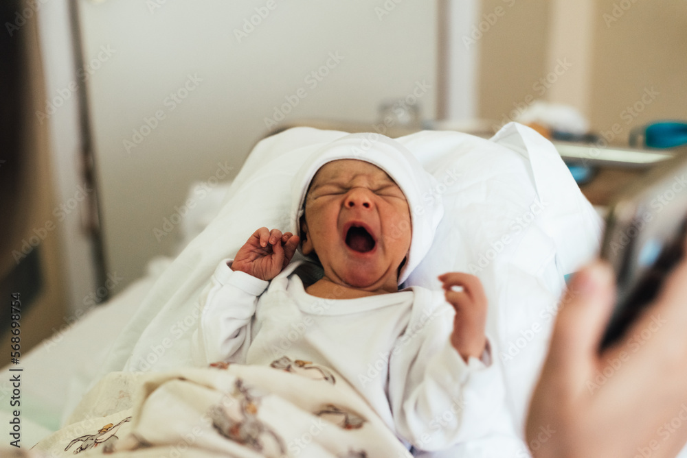 Newborn baby crying in his mother's arms in a hospital bed. Stock Photo ...