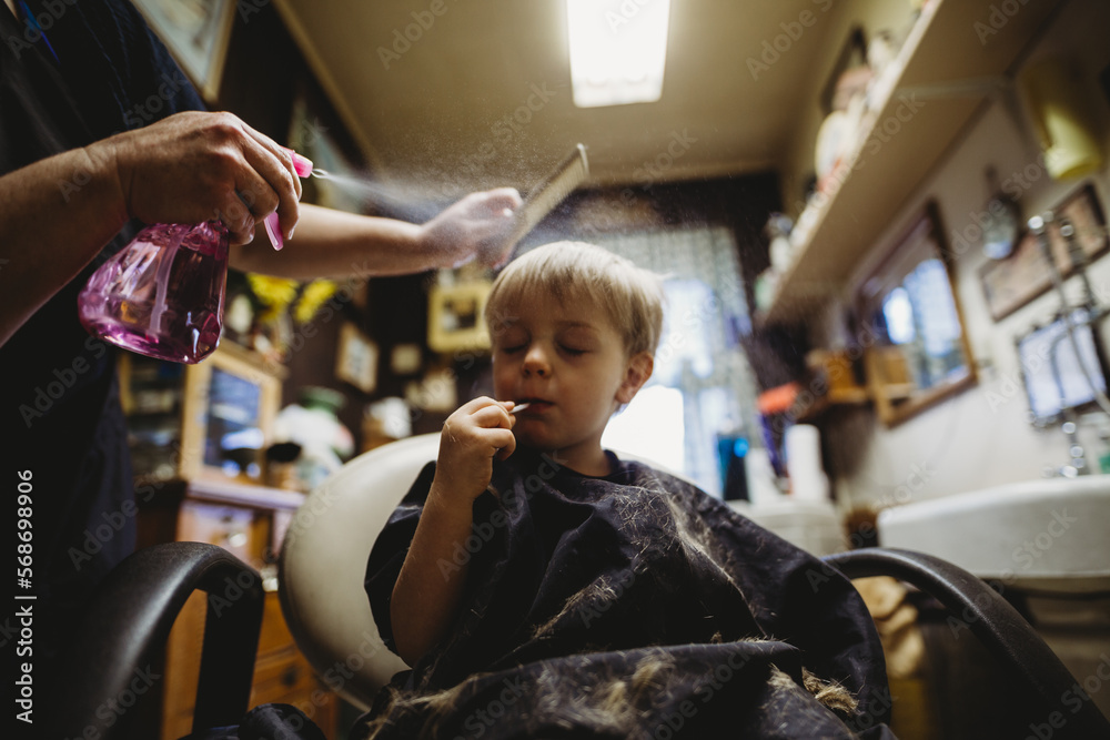 Little boy enjoying a sucker during a haircut at a barber shop Stock ...