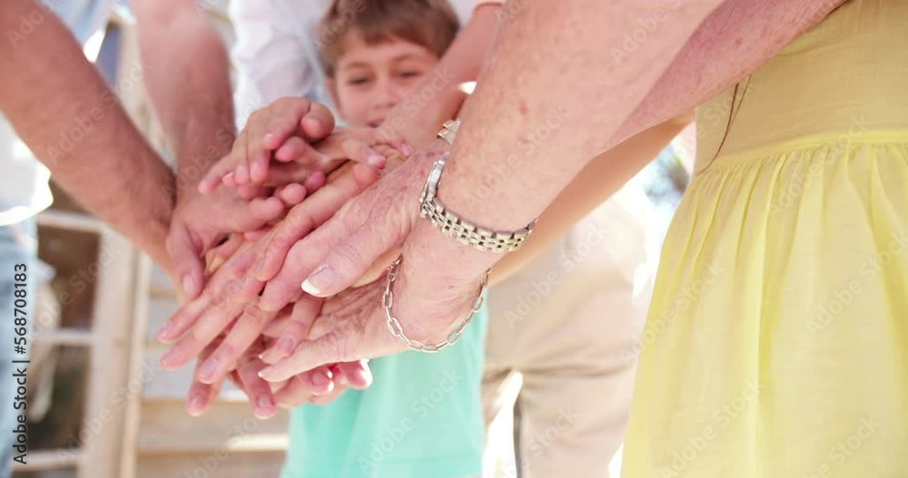 Three generation family putting their hands together in a circle in a ...