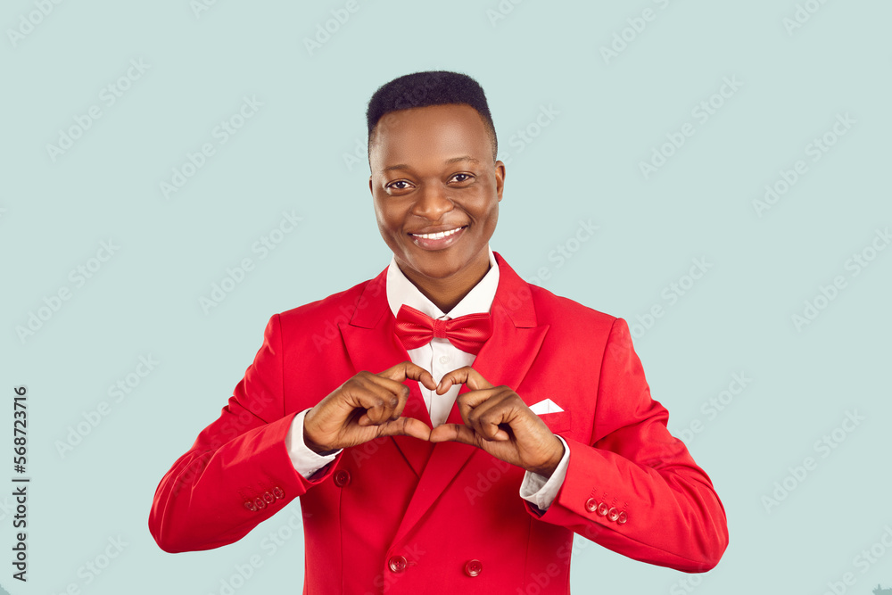 Handsome adult Afro American man in red suit makes hand heart shape ...