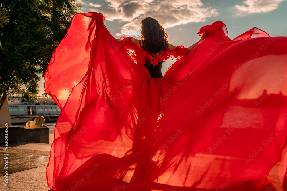Sunrise red dress. A woman in a long red dress against the backdrop of ...