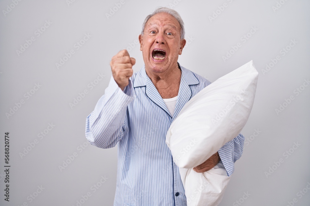Senior man with grey hair wearing pijama hugging pillow angry and mad ...