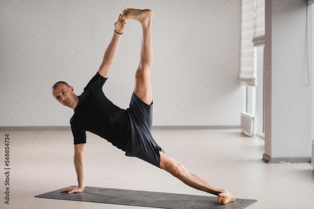 Foto de An athletically built man does yoga in the gym on a mat do ...