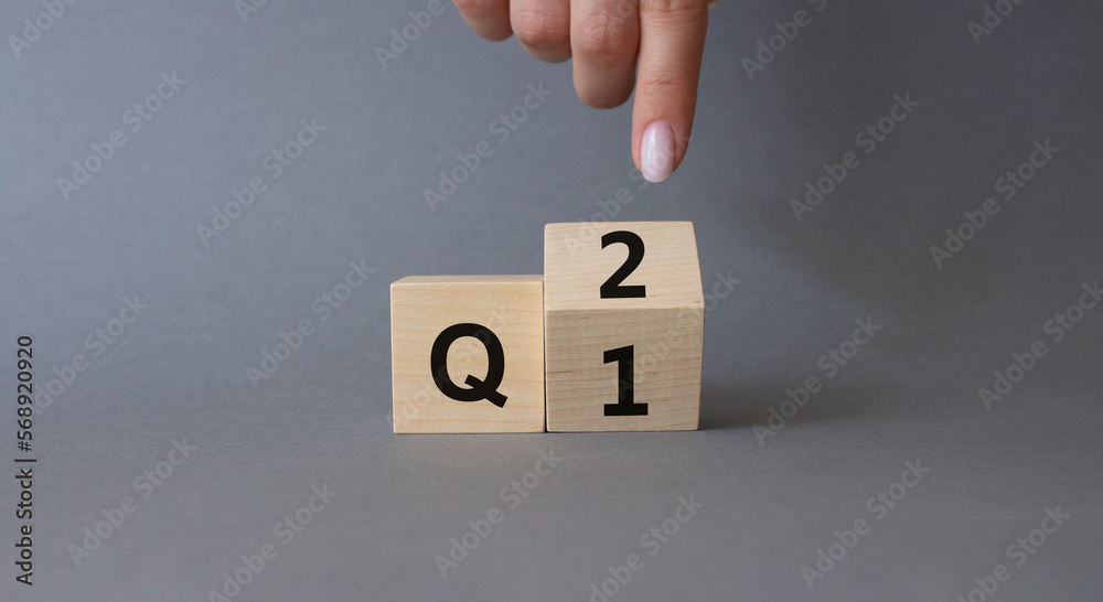 From 1st Quarter to 2nd symbol. Businessman hand points at turned wooden cubes with words 1st ...