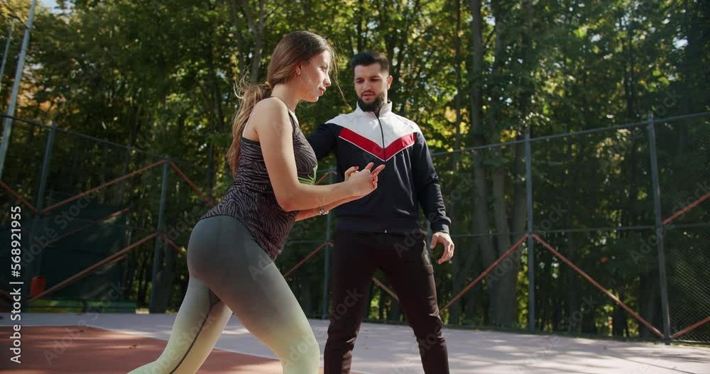 Vidéo Stock Trainer male correcting fit woman does gym exercises ...