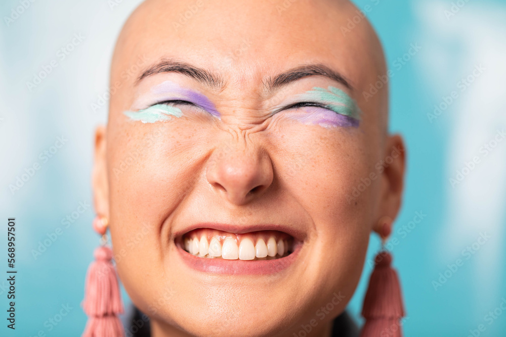 Stylish Gen Z woman wearing colorful makeup in front of blue backdrop ...
