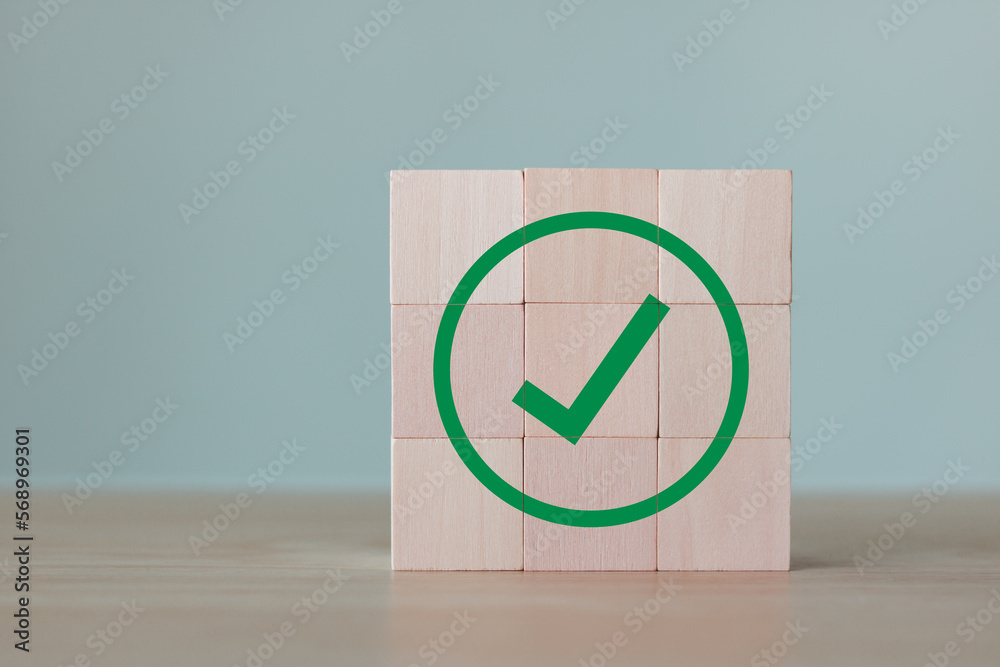 Wooden cube block with green checkmark icon stack on table and gray ...