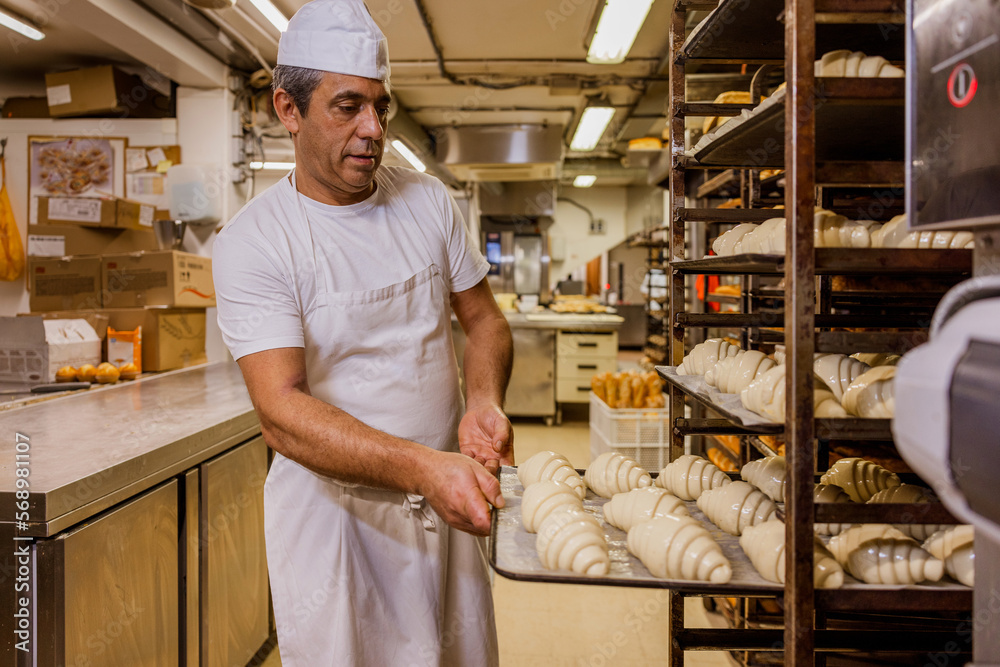 Male baker checking uncooked croissants Stock Photo | Adobe Stock