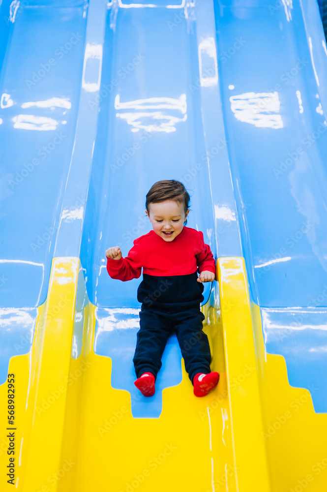 Happy, smiling little boy, preschool child descends, slides down a ...