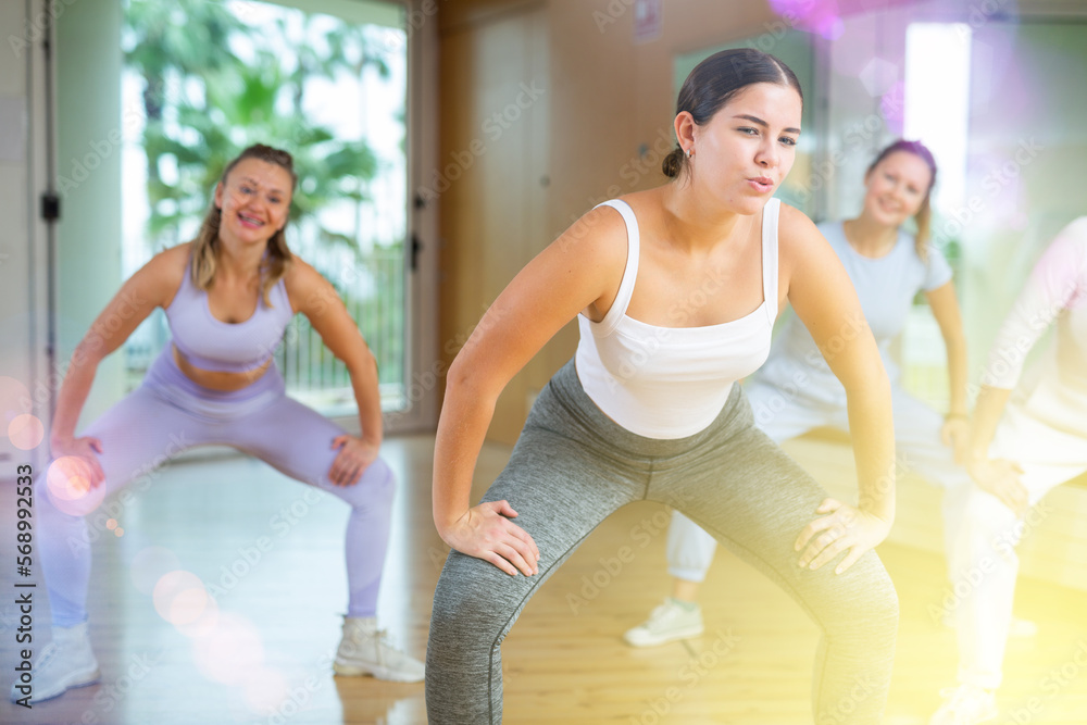 Excited sportive women of different ages dancing with legs wide apart ...