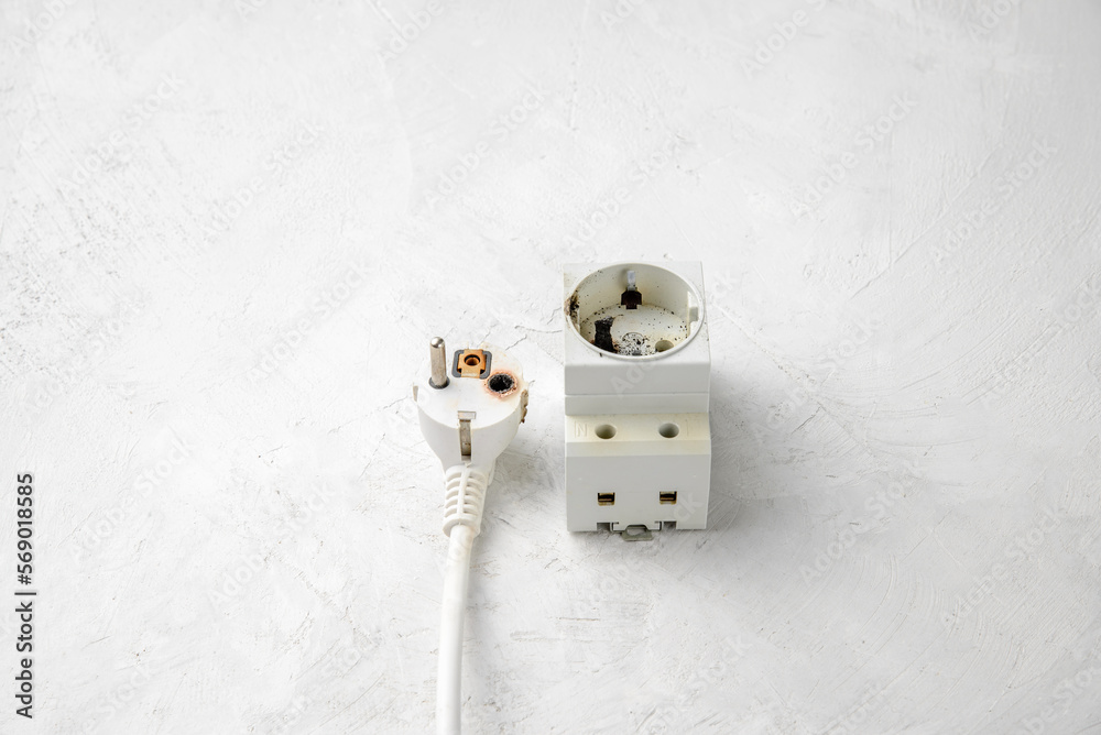 Short electrical circuit in the network. Burnt plug and socket close-up ...