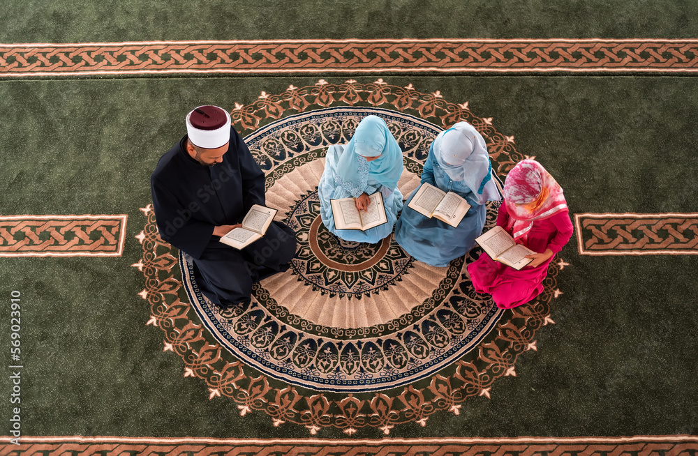 A Muslim teacher teaches children girls to read a holy book Quran ...
