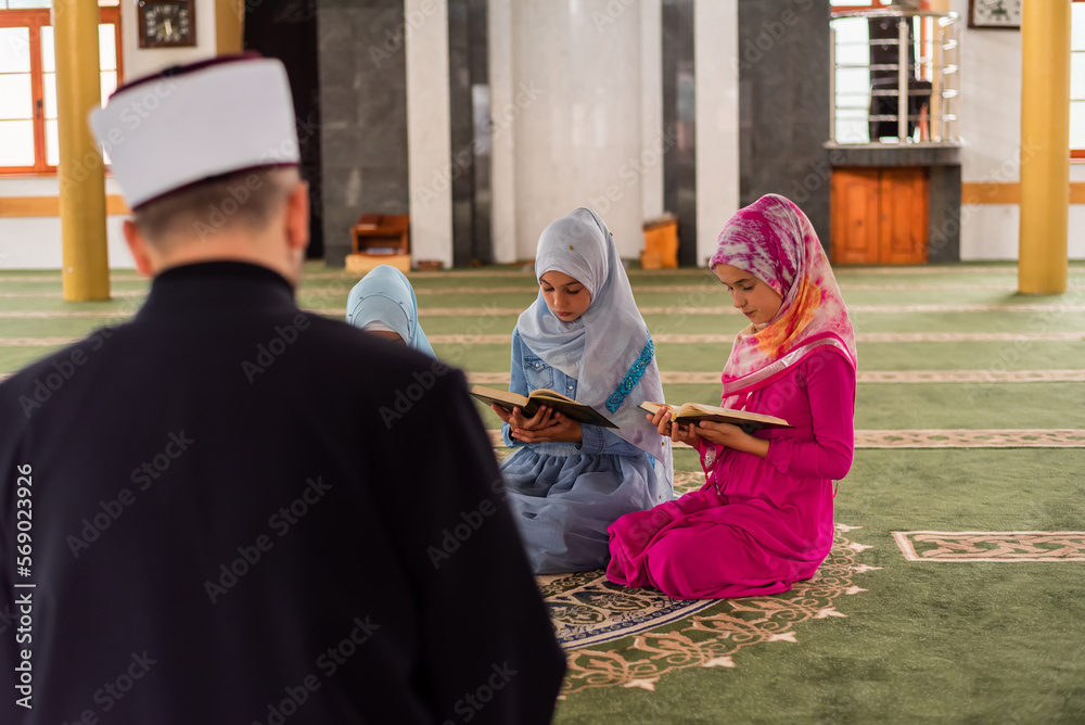 A Muslim teacher teaching child girls to reading a holy book Quran ...
