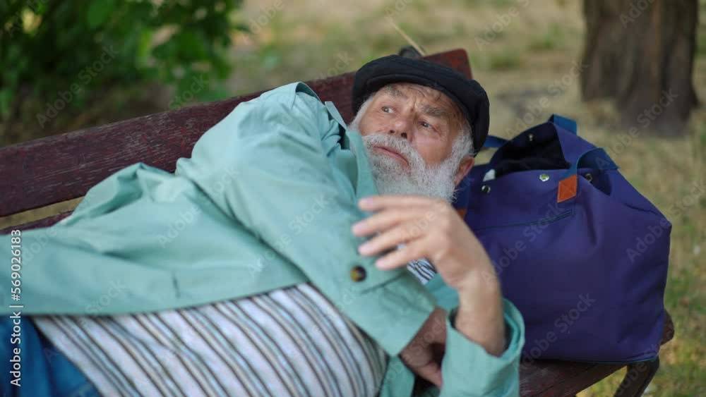 Portrait of senior sleeping homeless man waking up sitting down on ...