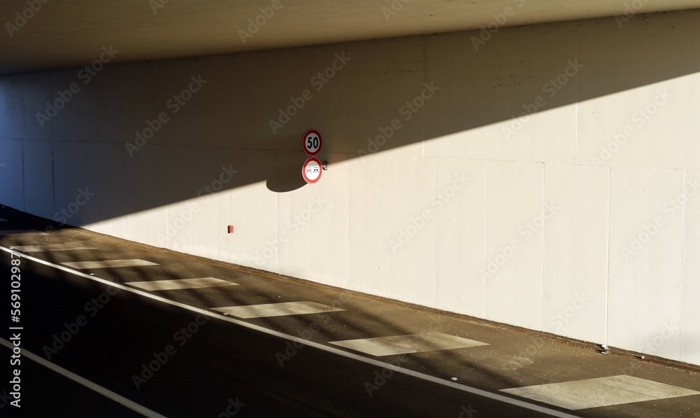 Inside of an underpass with concrete wall with two road sign, divided ...