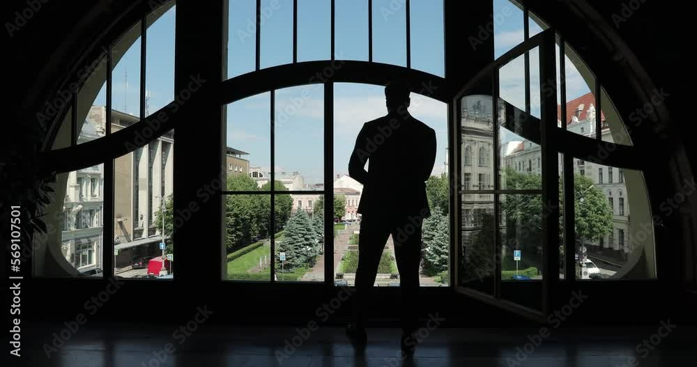 backlight, plan. a man walks to the window and puts on his tuxedo ...