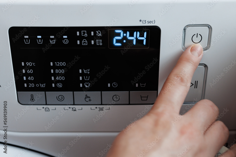 Hand turning on and off the switch of the washing machine. Person's ...