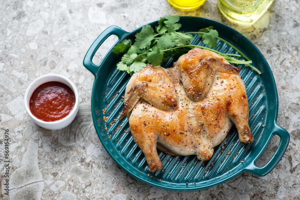 Roasted chicken tabaka on a green serving tray, horizontal shot on a ...