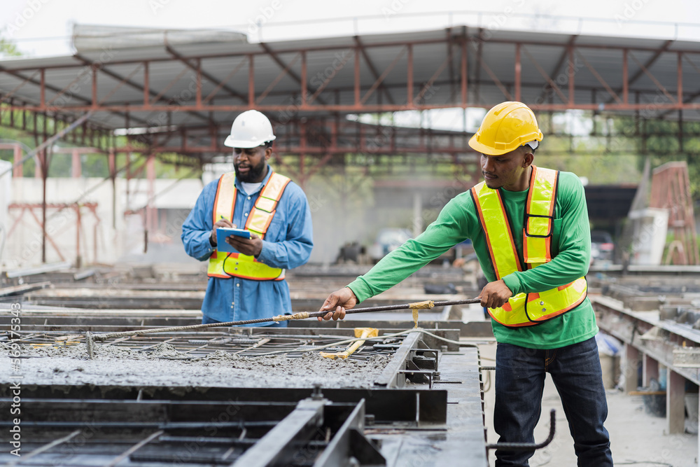Construction worker uses long steel trowel spreading wet concrete ...