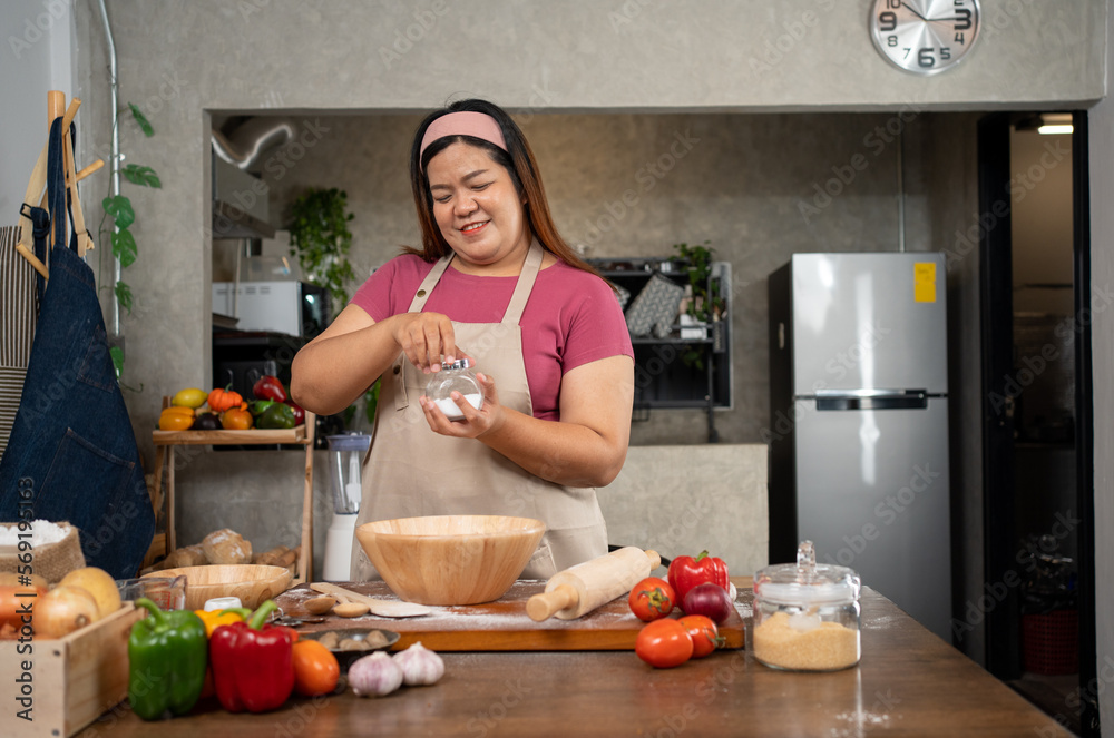 Portrait of obese woman cooking pizza in the kitchen, Raw pizza in the ...