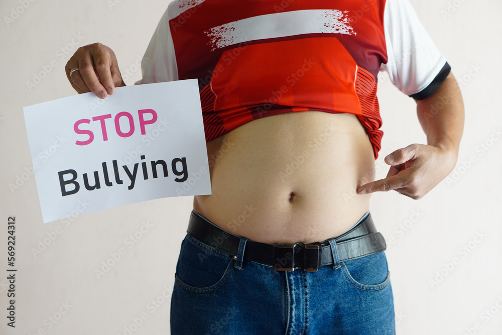 Closeup man with his big belly holds paper sign with word " STOP ! Bullying " Concept, campaign ...