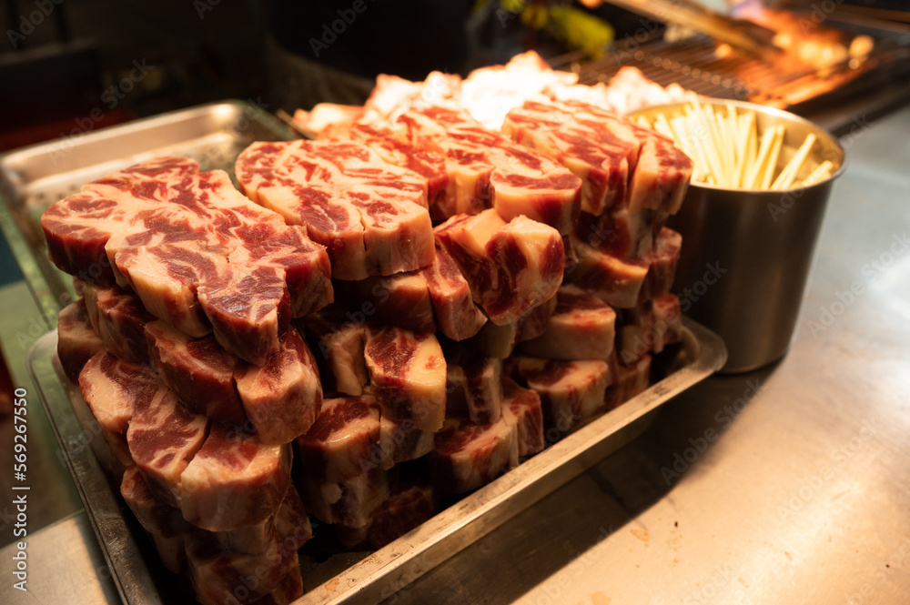 Closeup of pieces of freshly cut and chopped red meat on barbeque for ...