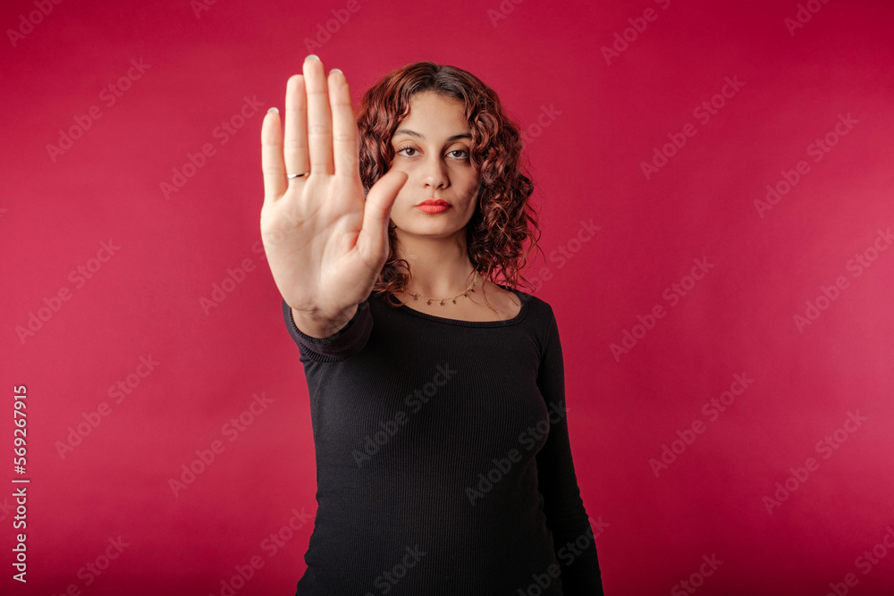 Redhead millennial woman wearing black dress standing isolated over red ...