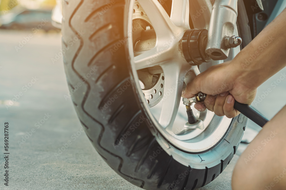 Hands of man check inflator pressure and inflates a tire on motorcycle ...