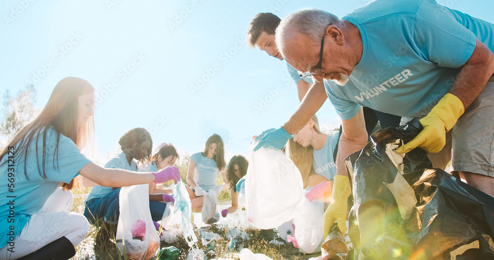 Enthusiastic volunteers of different ages picking up plastic bottle ...