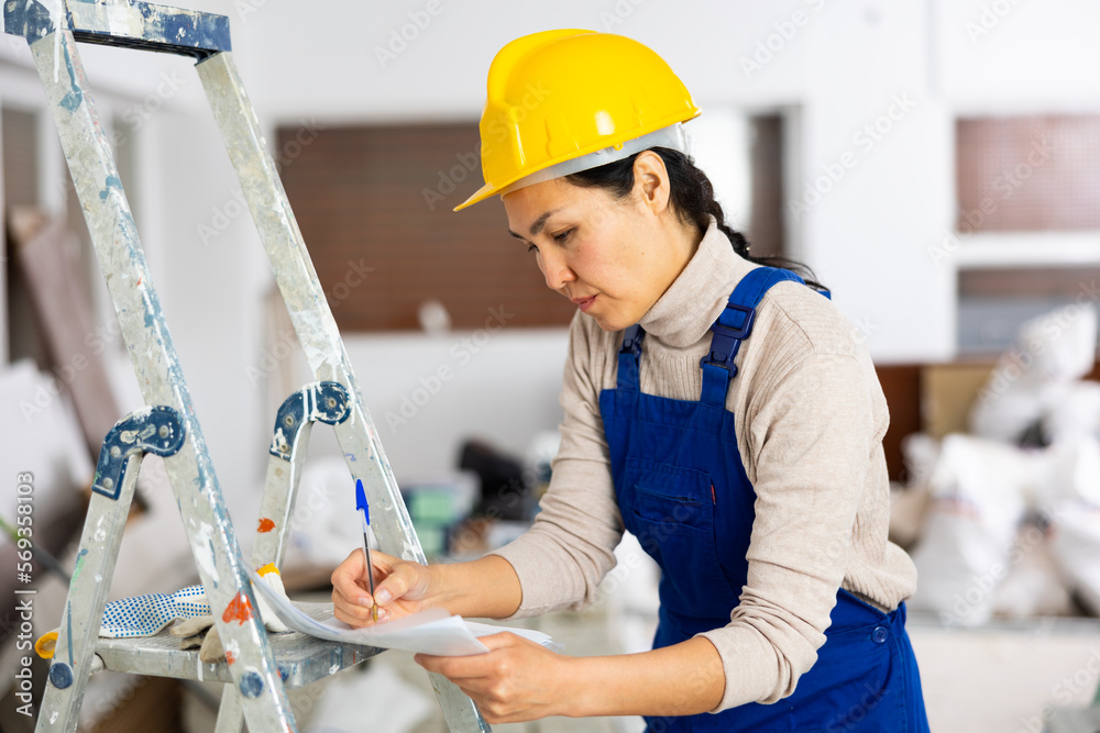 Female Asian engineer writing in check list during repair works in ...