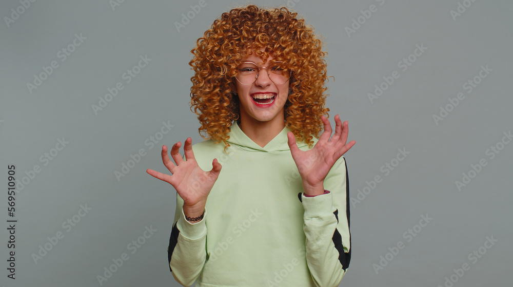 Funny furious teenager girl with curly frizzy hairstyle pretending to ...