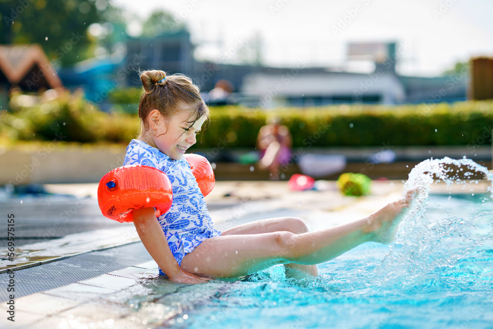 Little preschool girl with protective swimmies playing in outdoor ...
