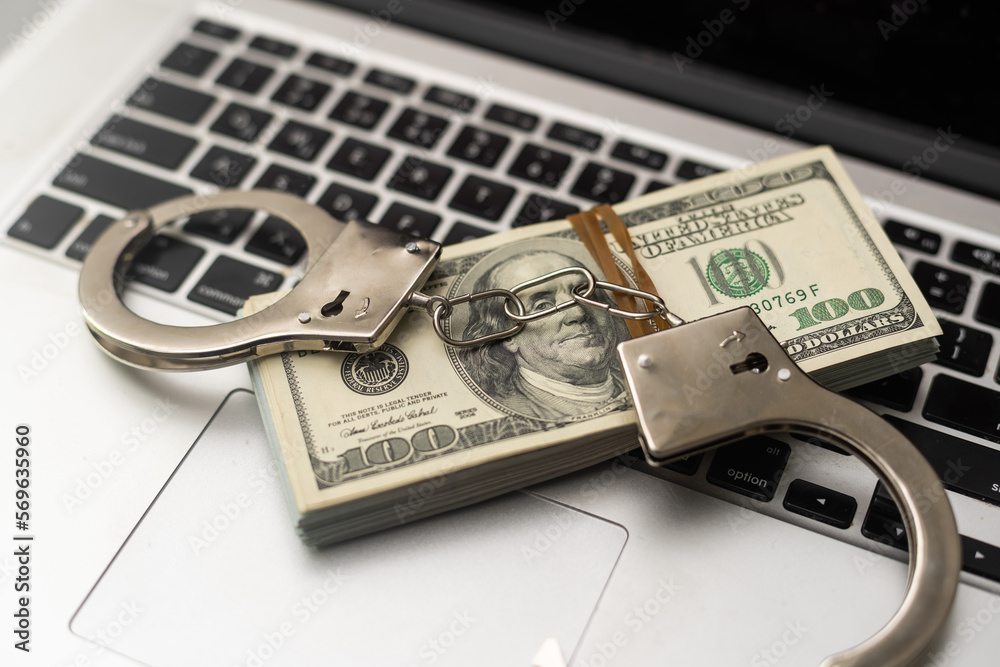 Cyber crime legal law police handcuffs on a hundred dollar bills with ...