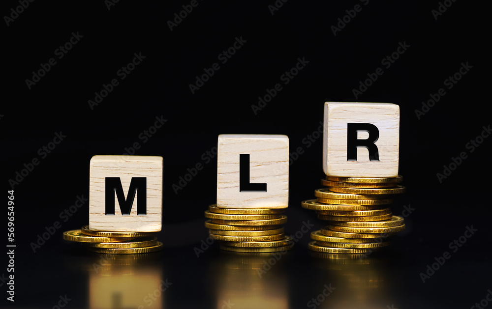 Text MLR (Minimum Loan Rate) on wooden blocks on stack of gold coins ...