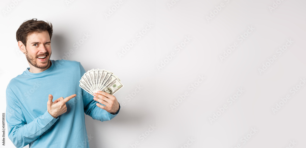 Handsome rich guy winking at camera, showing income, pointing finger at ...