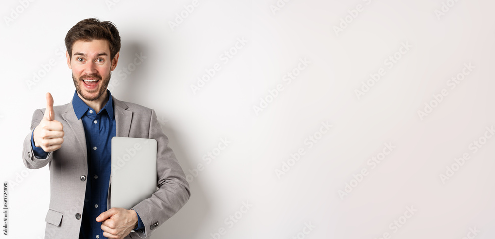 Good job. Happy smiling business man in suit holding laptop, showing ...