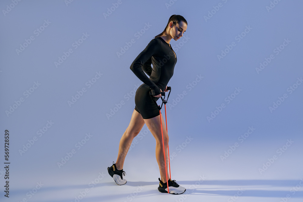 Woman performs exercises with expander on studio background. Strength ...