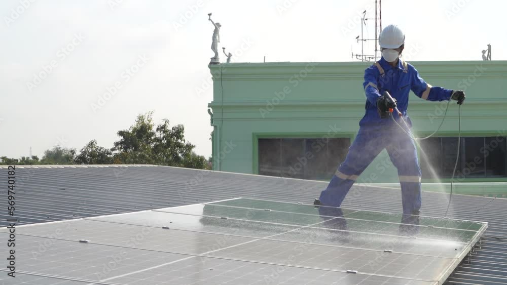 Technician using high pressure water to clean the solar panels that are ...