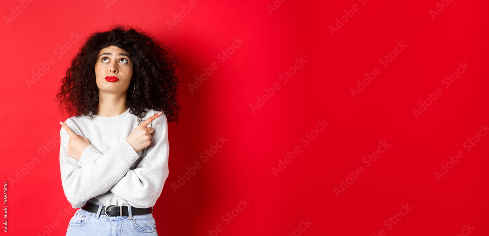 Indecisive female model with red lips and curly hair, looking up ...