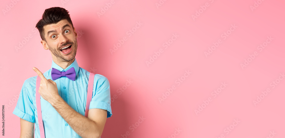 Funny male model in bow-tie, tilt head and pointing finger left ...