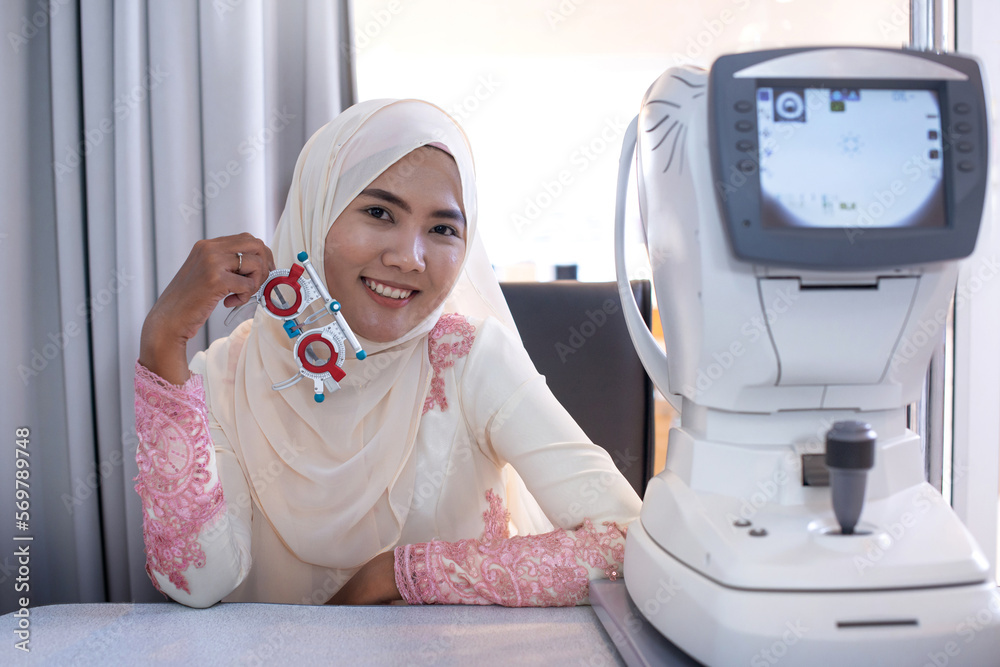 Muslim woman in hijab during optic test, holding trial frame for ...