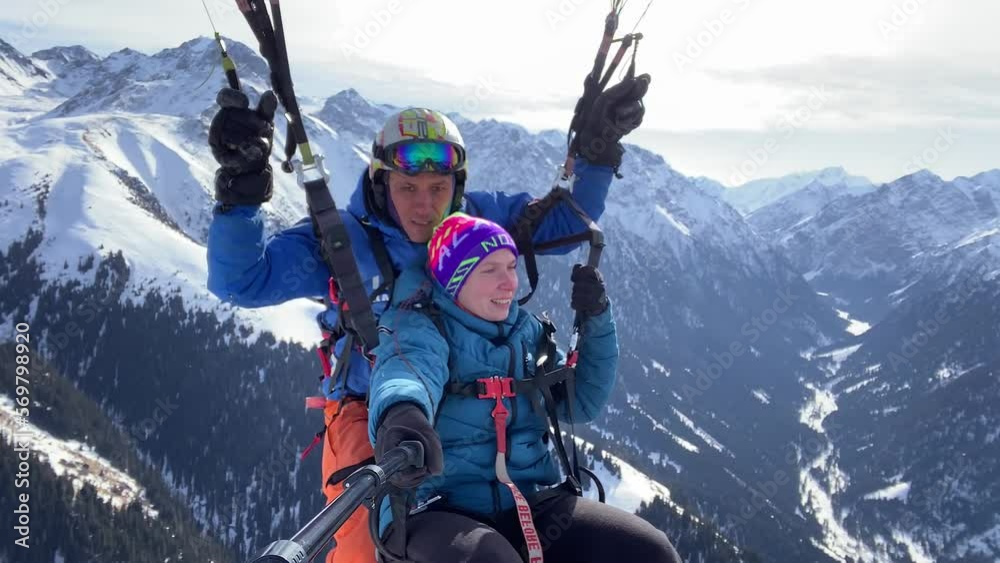 The girl is flying a paraglider with an instructor against the backdrop of majestic mountains ...