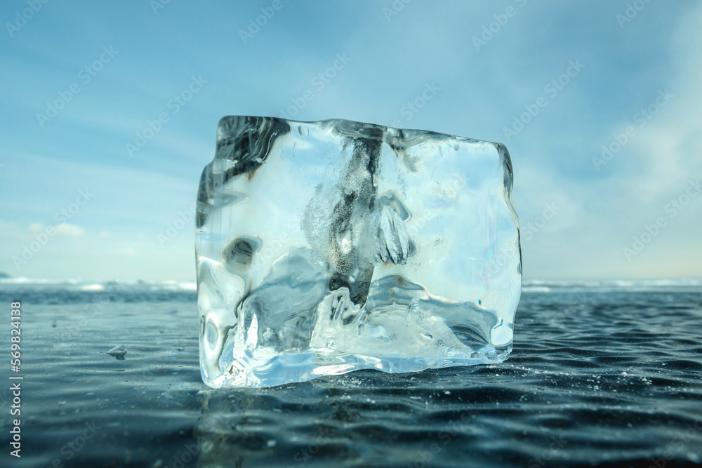 Transparent block of ice in the rays of the sun at sunset. Winter ...