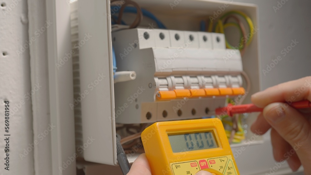 Work under voltage, electrician is checking serviceability of equipment ...