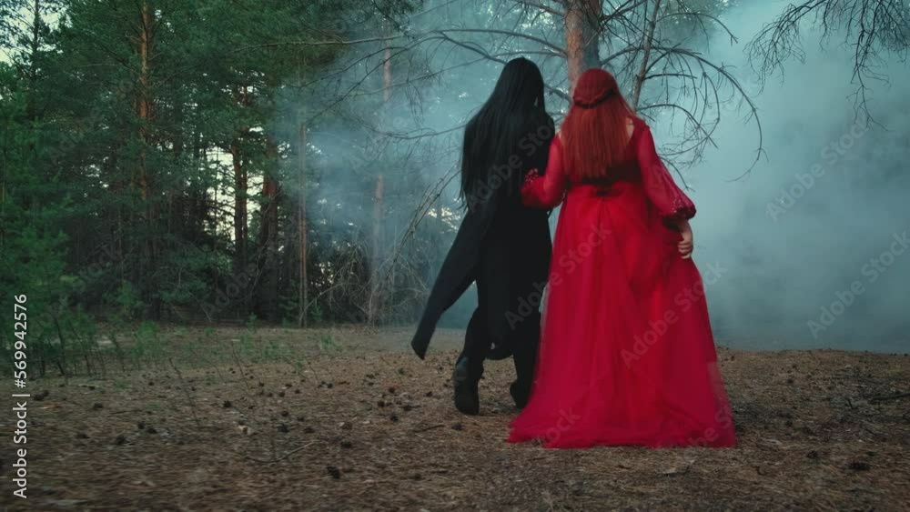 Goth man vampire in black tailcoat walking with gothic woman holding ...